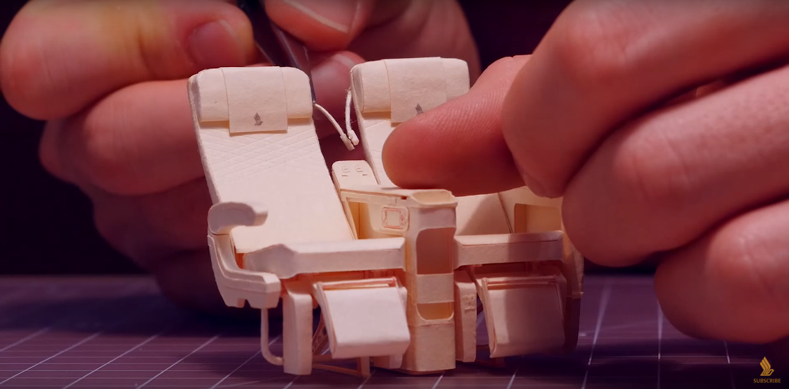 Artist takes paper planes to the next level, builds tiny seats complete ...